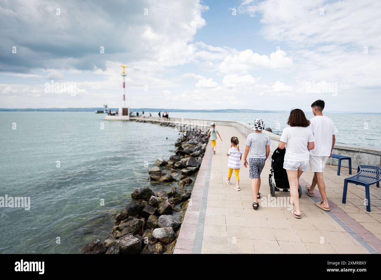 Family strolling along a seaside pier on a sunny day. Clear blue sky ...