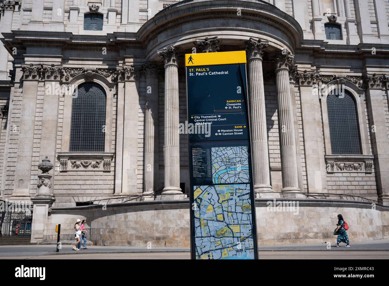A tourist looks up directions on a city street map in front of St Paul ...