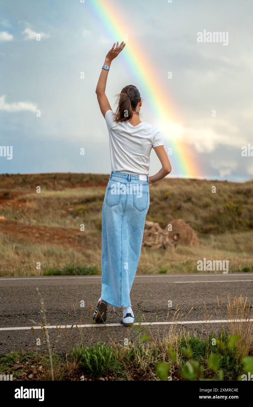 Brunette Girl in Denim Skirt and White Shirt on Road with Rainbow in ...