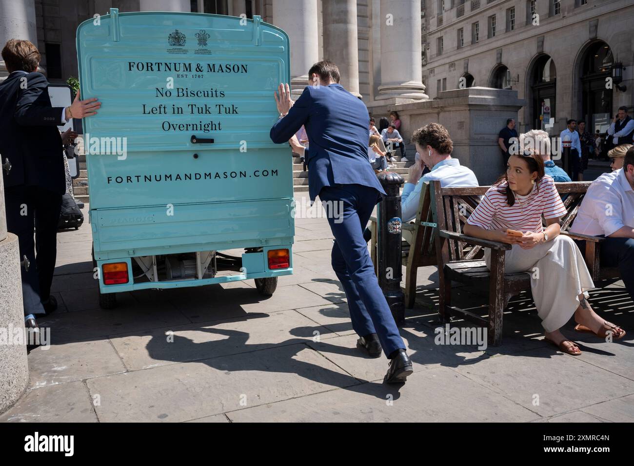 Two men in suits push a Fortnum & Mason Tuk Tuk through a narrow gap at ...