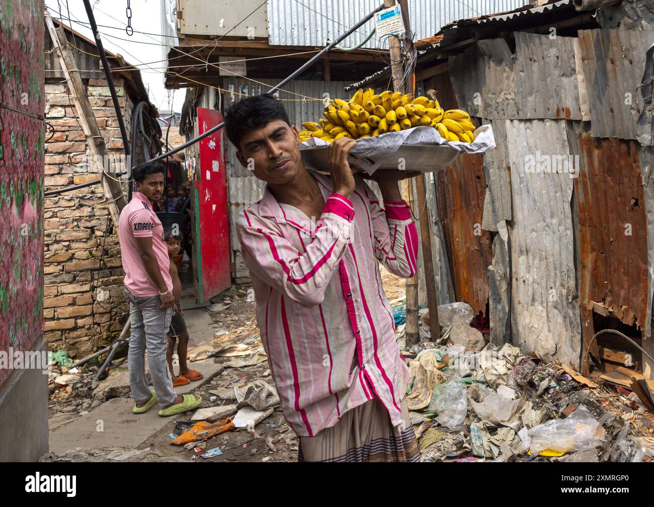 Bangladeshi man carrying bananas on his shoulder in the street, Dhaka Division, Dhaka ...