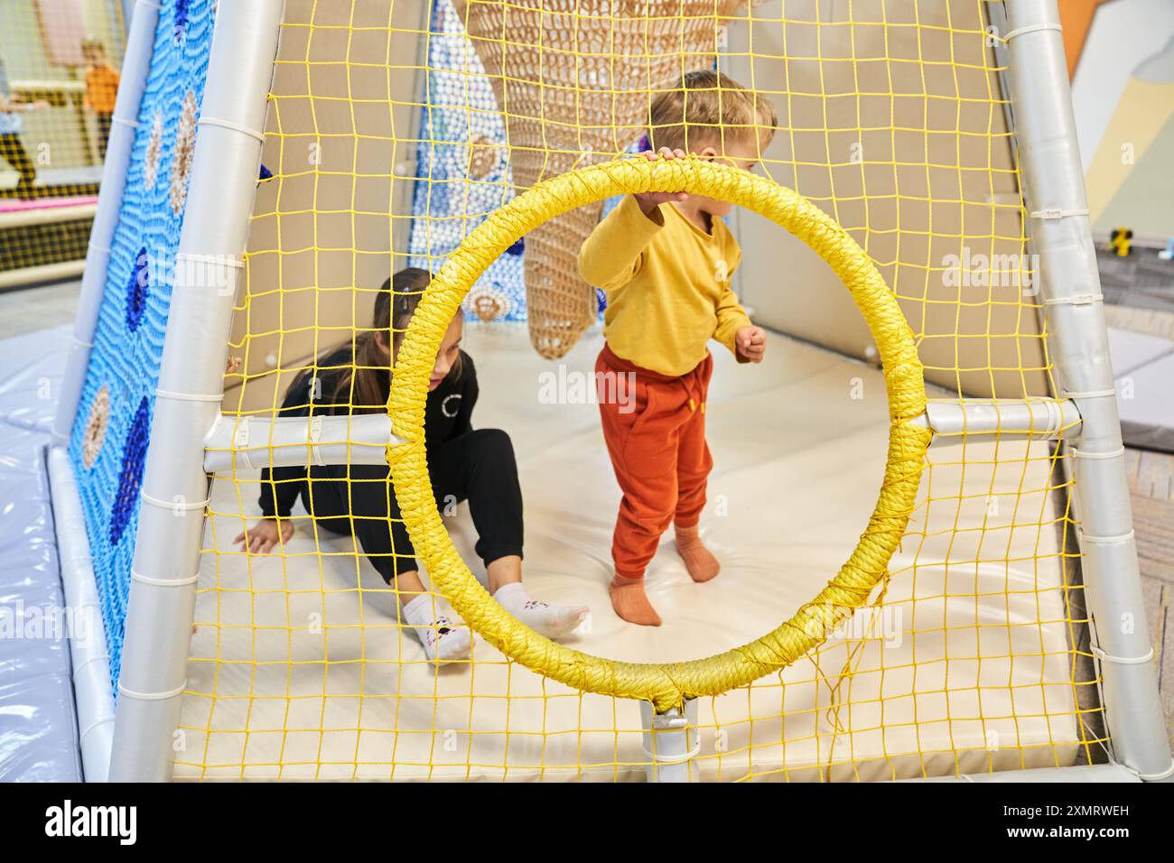 Two children on an indoor playground, unrecognizable children sitting ...