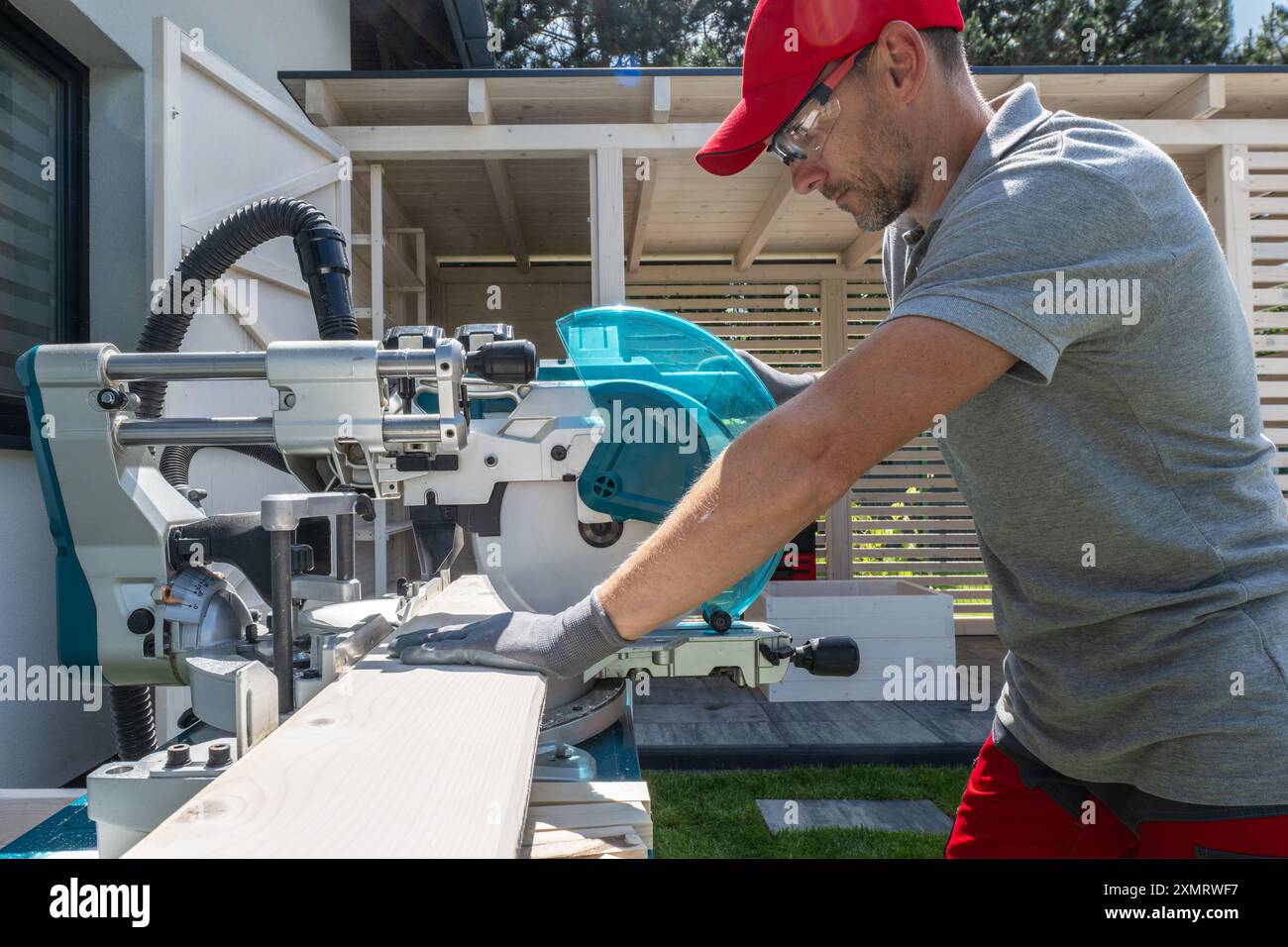 A skilled carpenter works meticulously with a miter saw, cutting wood ...