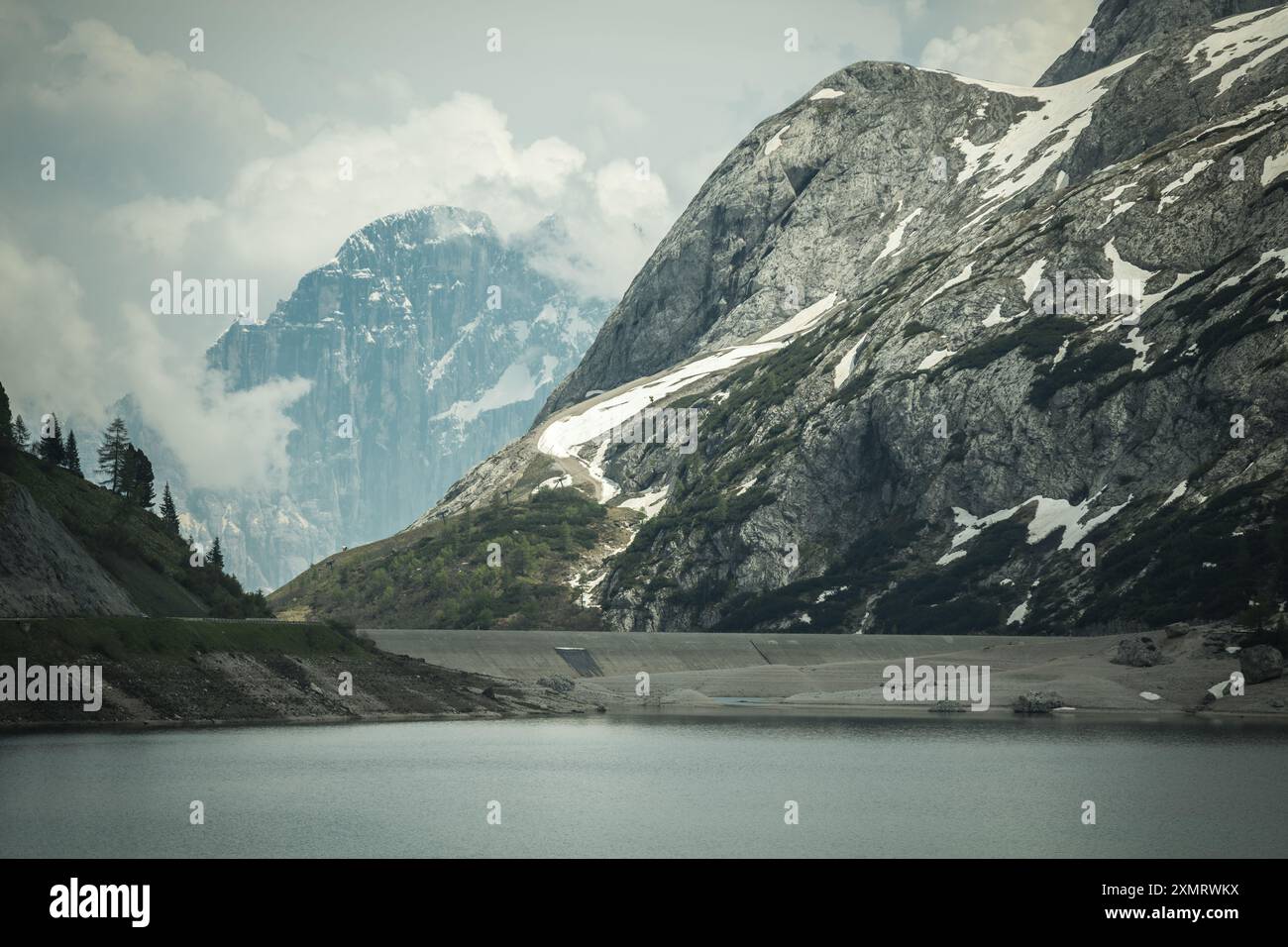 A peaceful alpine landscape features towering snow-capped mountains ...