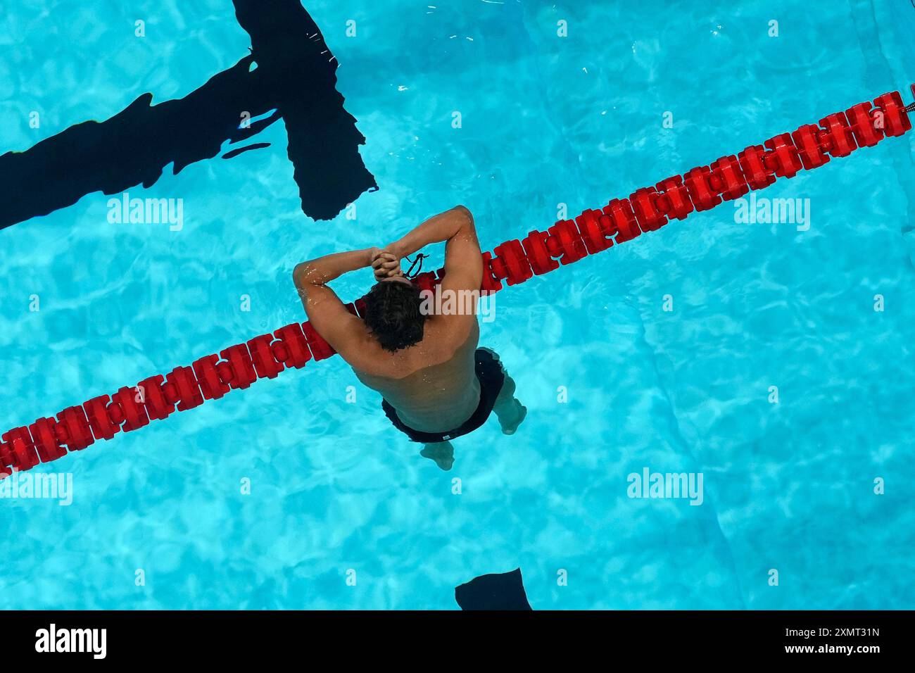 Thomas Ceccon, of Italy, hangs on the ropes after winning the men's 100 ...