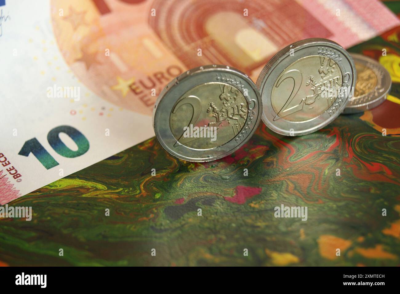 2 euro coins and a banknote on a motley background Stock Photo - Alamy