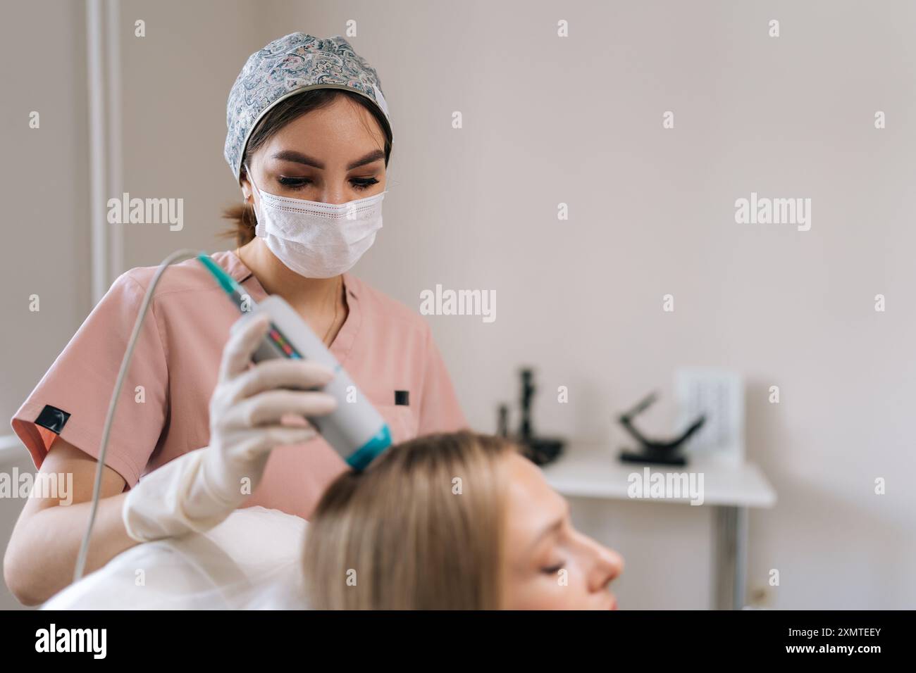 Skilled trichologist in gloves and mask performing hair treatment ...