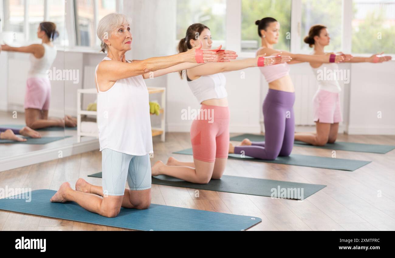 Senior lady exercising with resistance loop band during pilates class ...