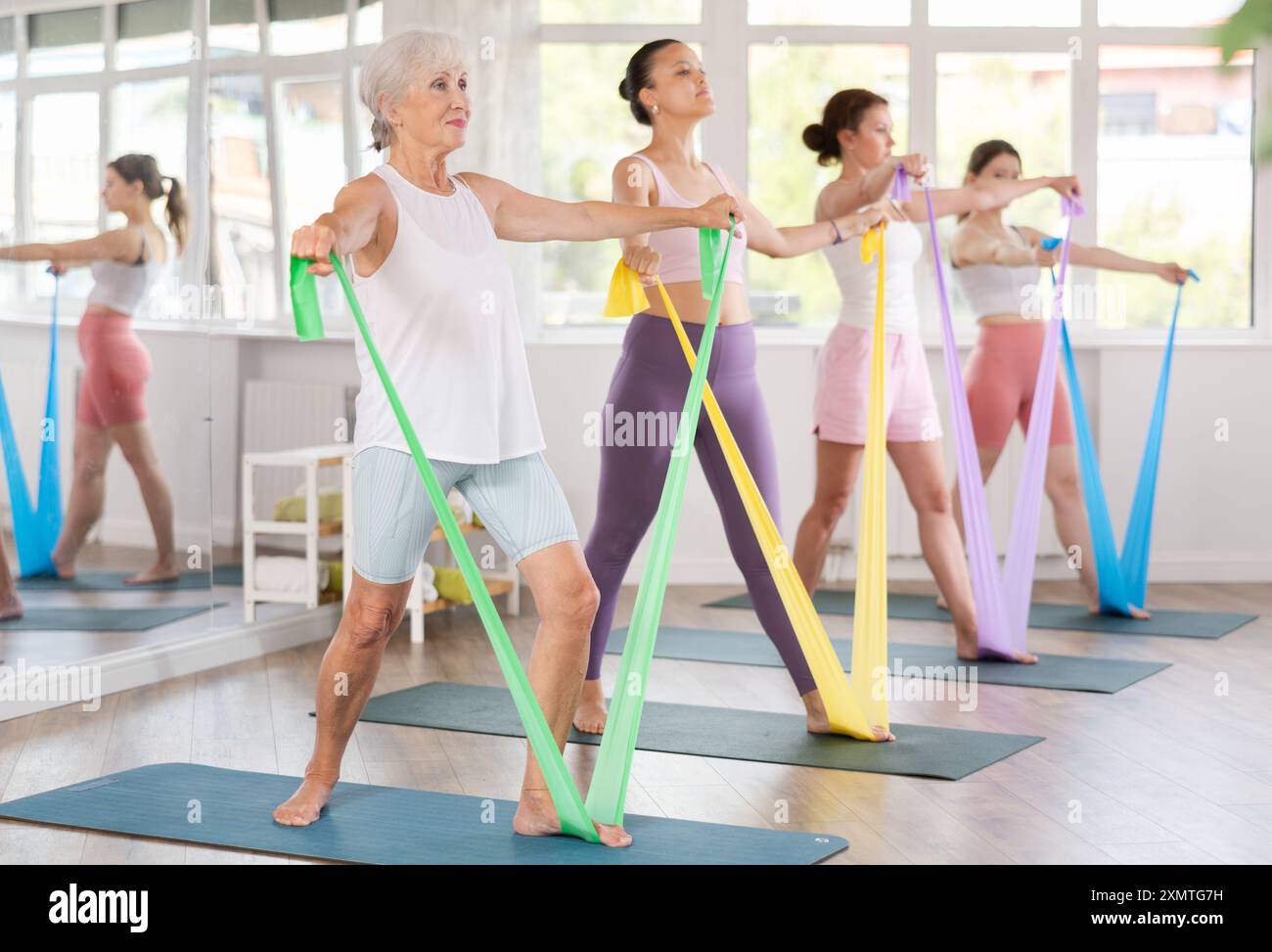 Senior lady performing exercises with resistance band in pilates class ...