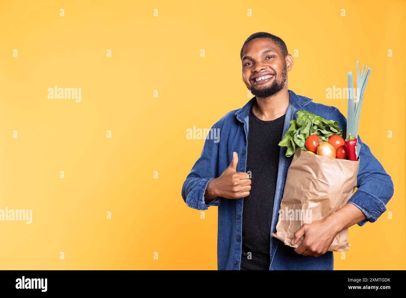 Smiling pleased male model gives shows thumbs up symbol in studio ...