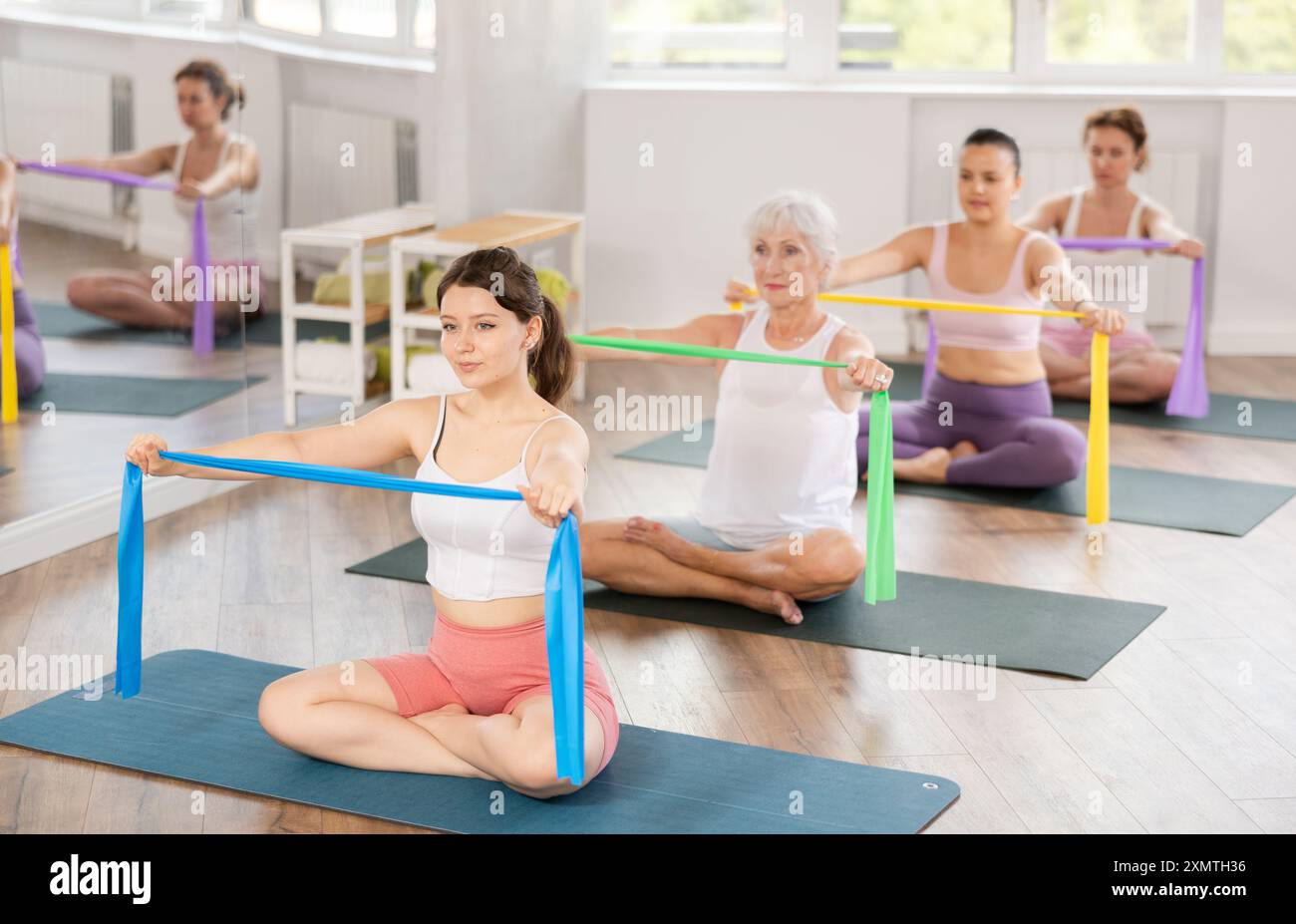 Group Pilates classes - woman doing body stretching using elastic bands ...