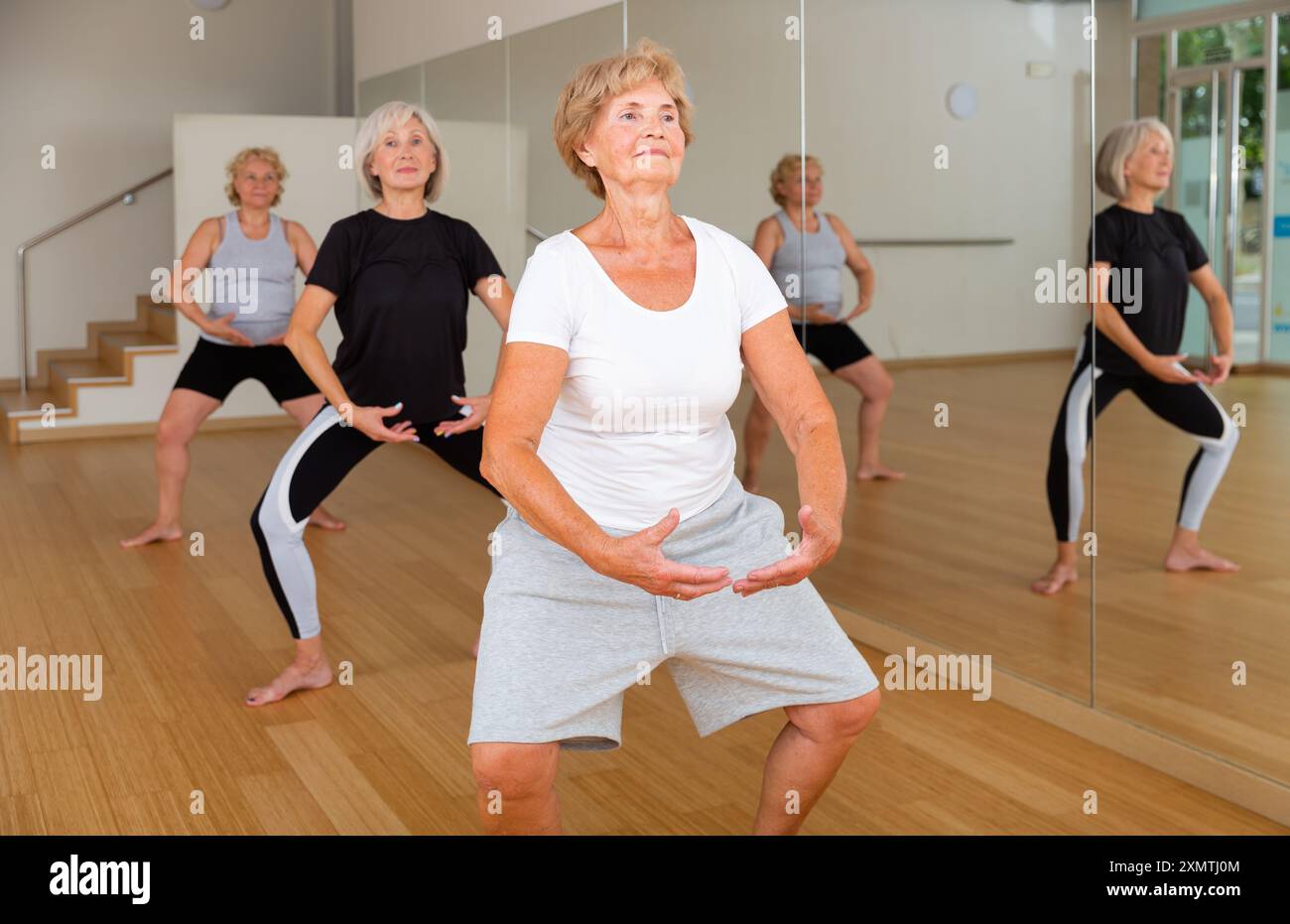 Mature women perform a plie squat while in the position of a ballet ...