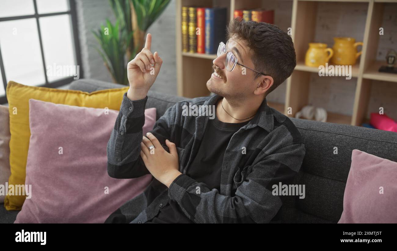A thoughtful hispanic man with a moustache sits comfortably indoors ...