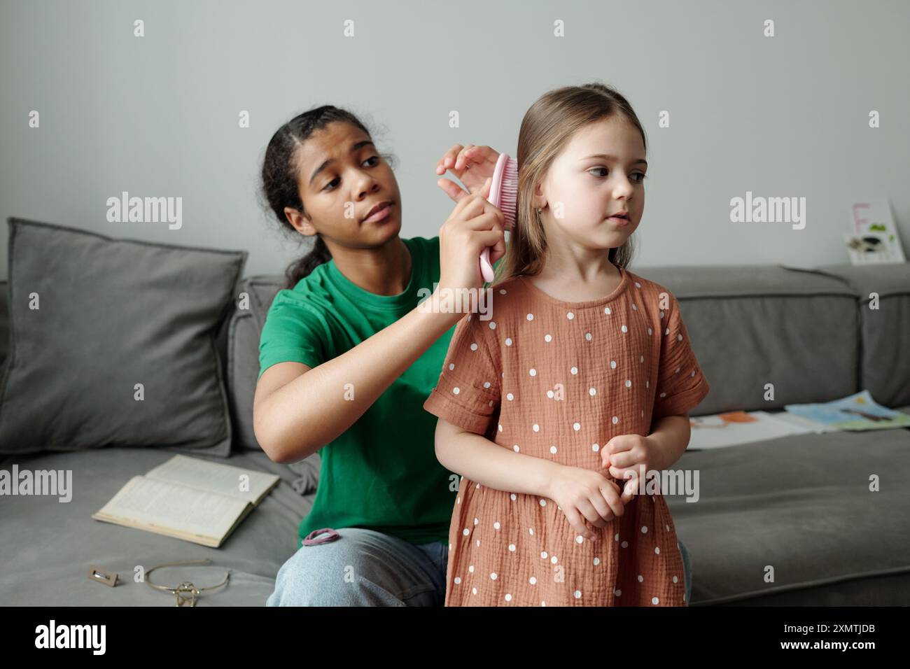 Cute teenage baby sitter brushing long thick hair of adorable child ...