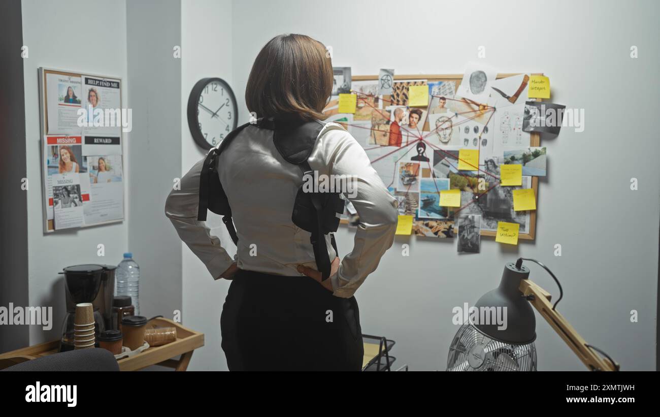 A woman detective examines a crime investigation board in an office ...