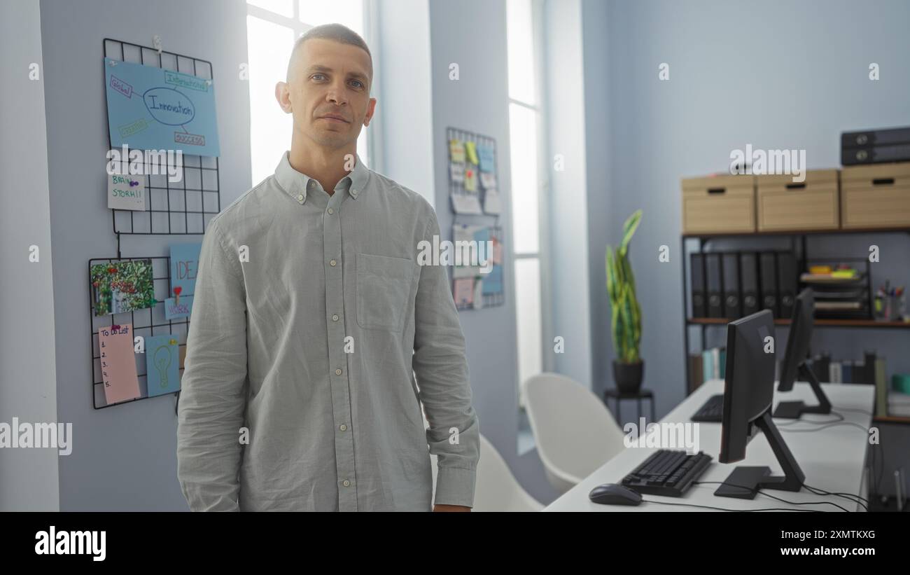 Young man standing in an office room with a wall full of notes and two ...