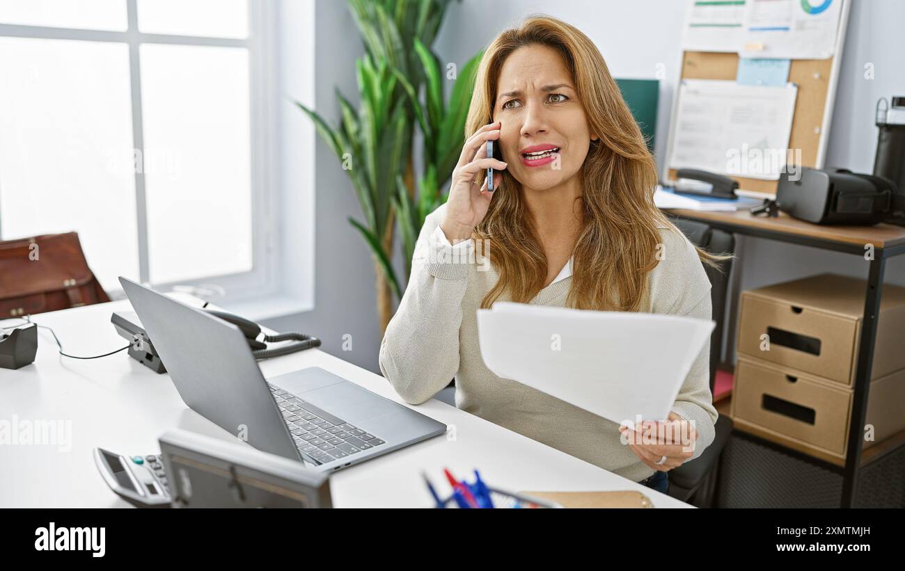 Confused hispanic woman answering phone call holding documents in ...