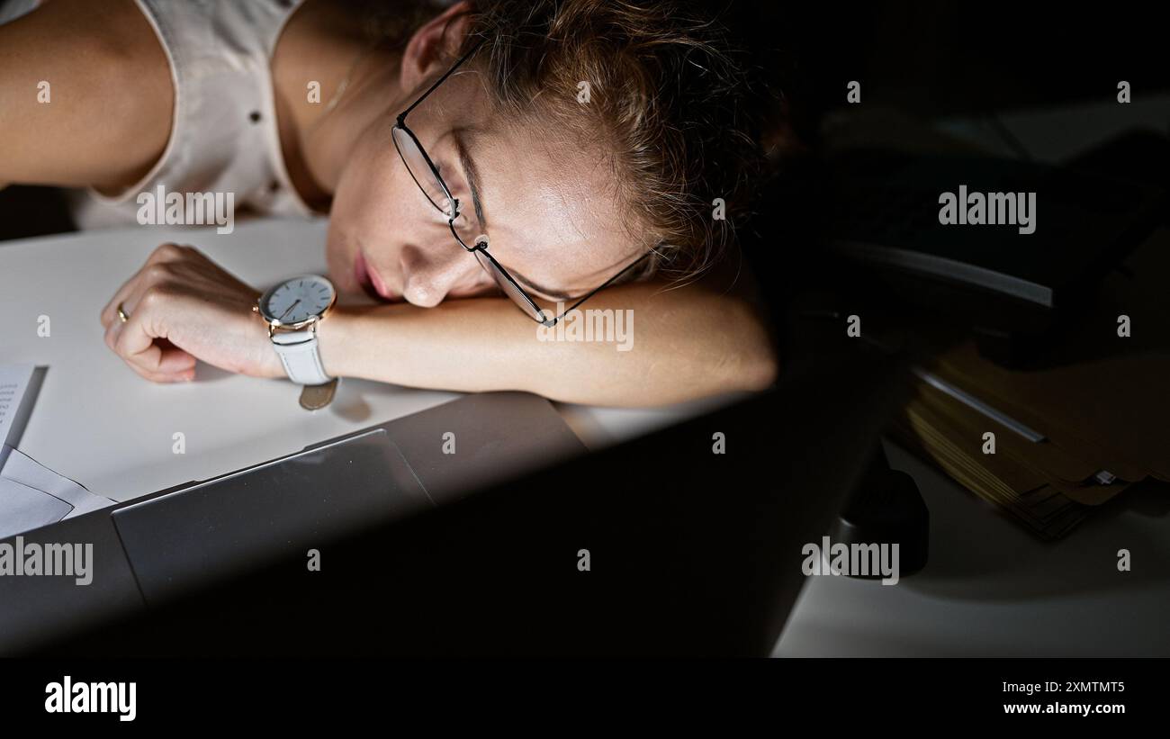 Overworked caucasian woman asleep at the office during night, with ...