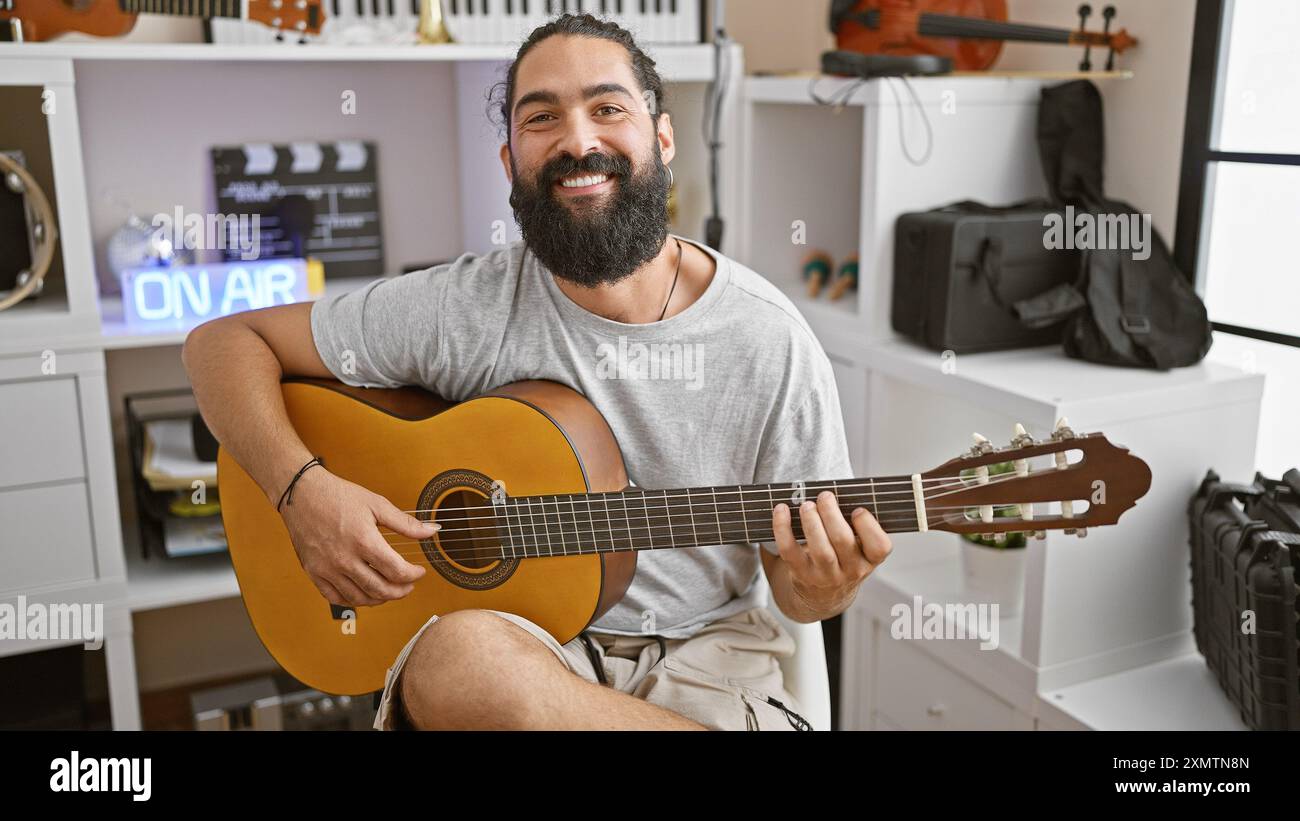A smiling man with a beard plays an acoustic guitar in a cozy music ...