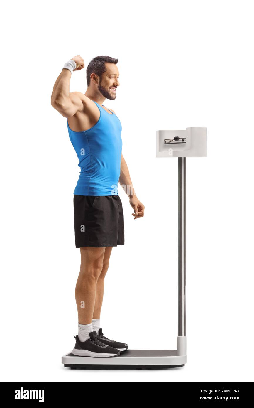 Male athlete standing on a medical weight scale and flexing arm muscle ...