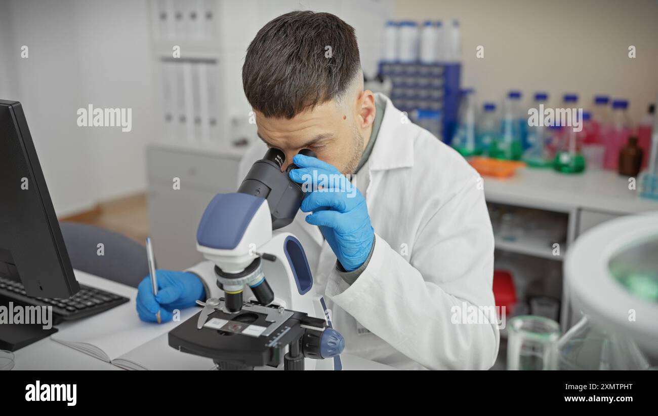 Hispanic man with beard in lab coat using microscope in science ...