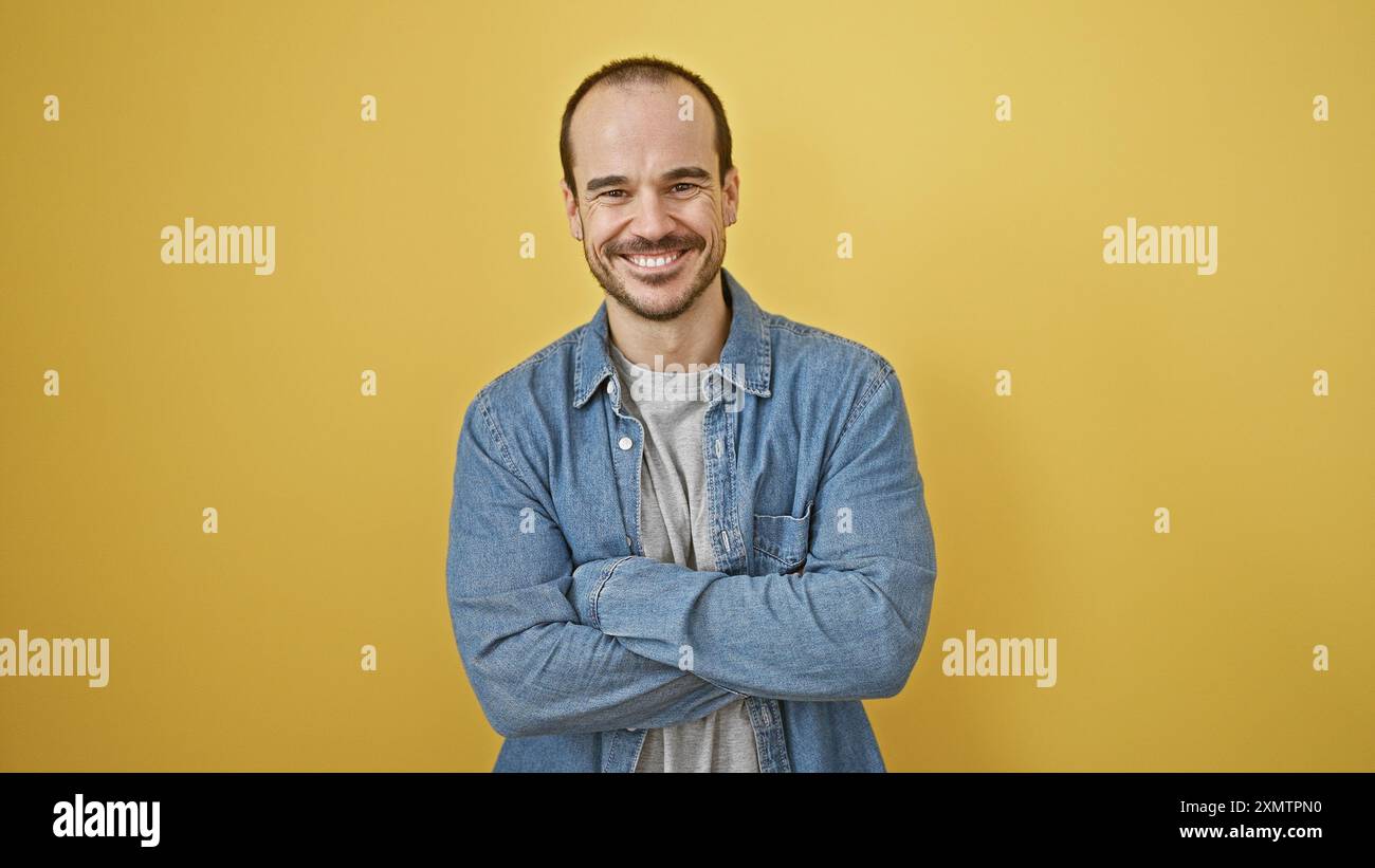 Confident bald man with beard in denim shirt, arms crossed, smiles ...