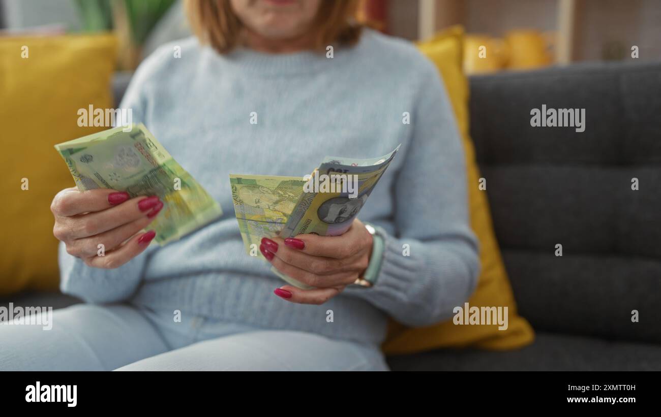 Middle-aged woman counting romanian currency in a cozy living room ...