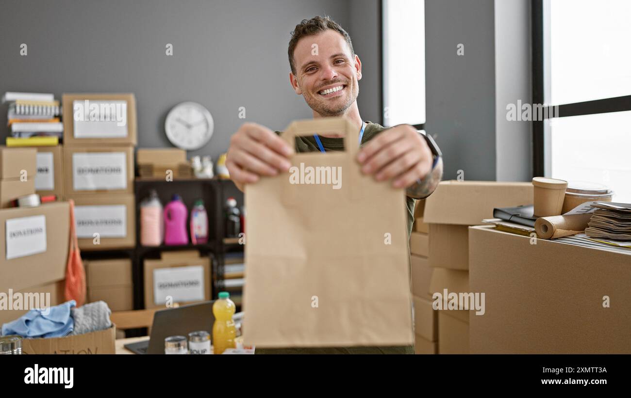 Smiling man offering paper bag in warehouse surrounded by boxes ...