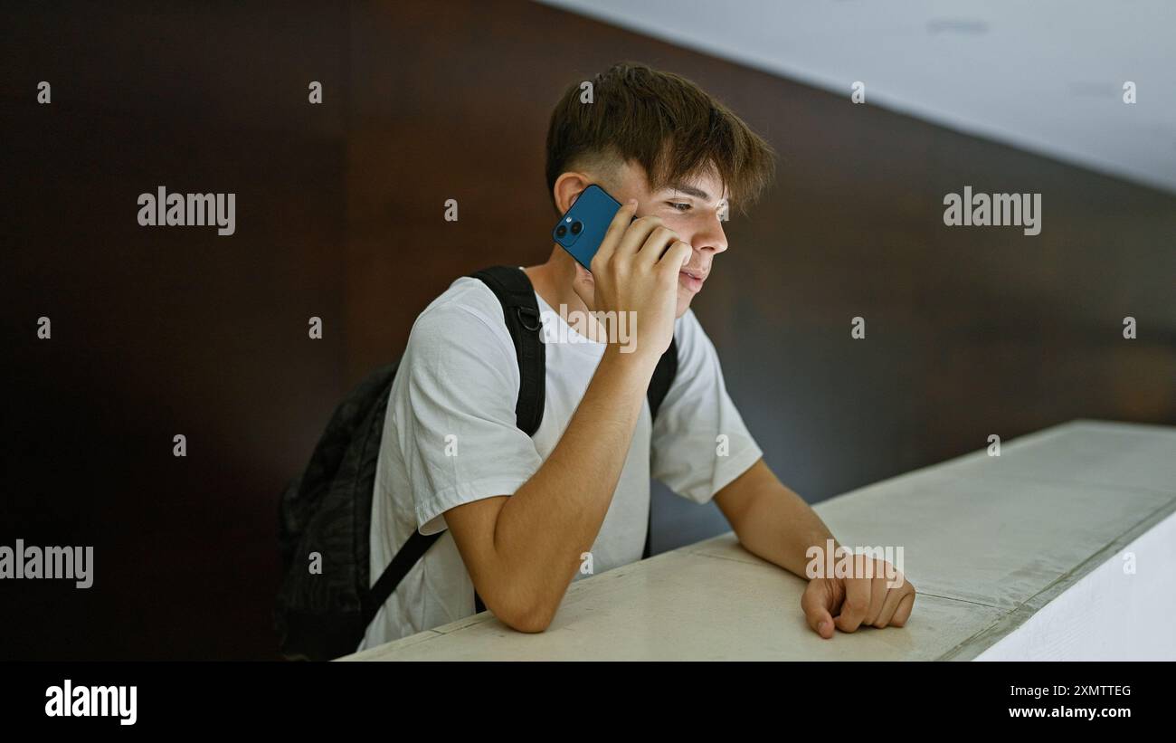 A young caucasian male student talks on a smartphone while leaning on a ...