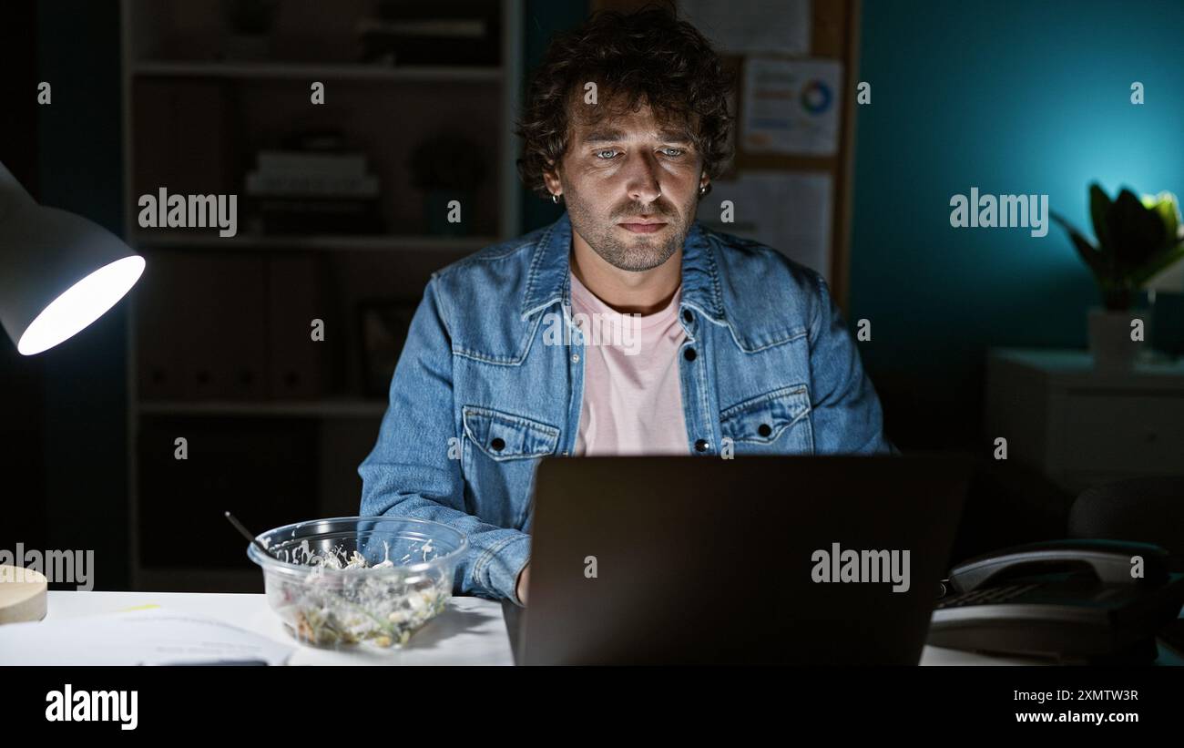 A young hispanic man works late at an office, depicting dedication with ...