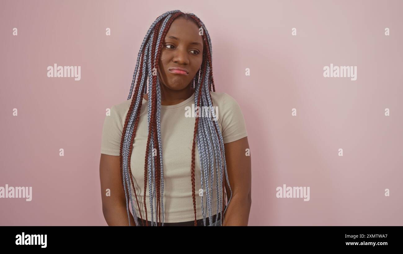 African american woman with braids poses against a pink isolated ...