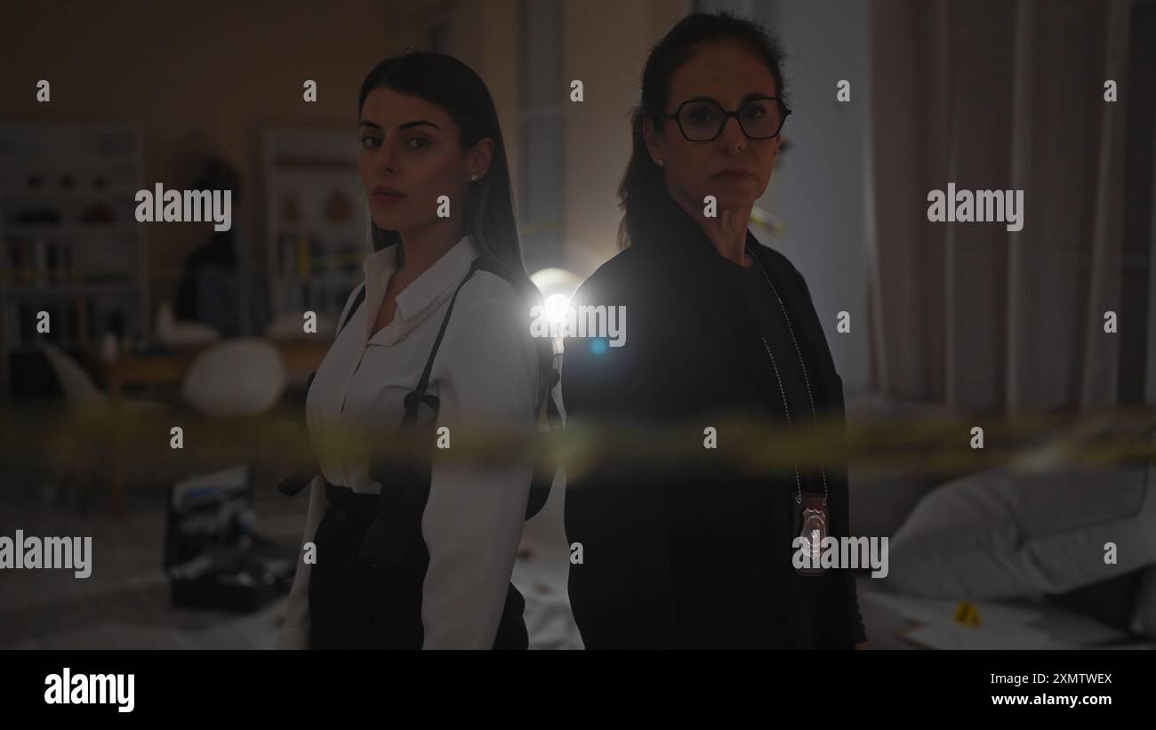Two women detectives investigate a crime scene indoors, circled by ...