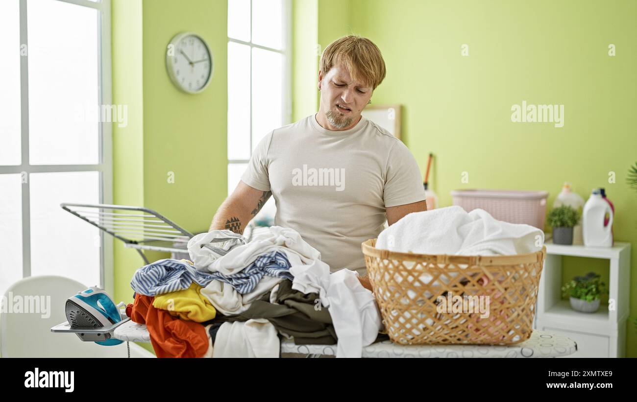 A blond man frustrated with household chores in a green laundry room ...