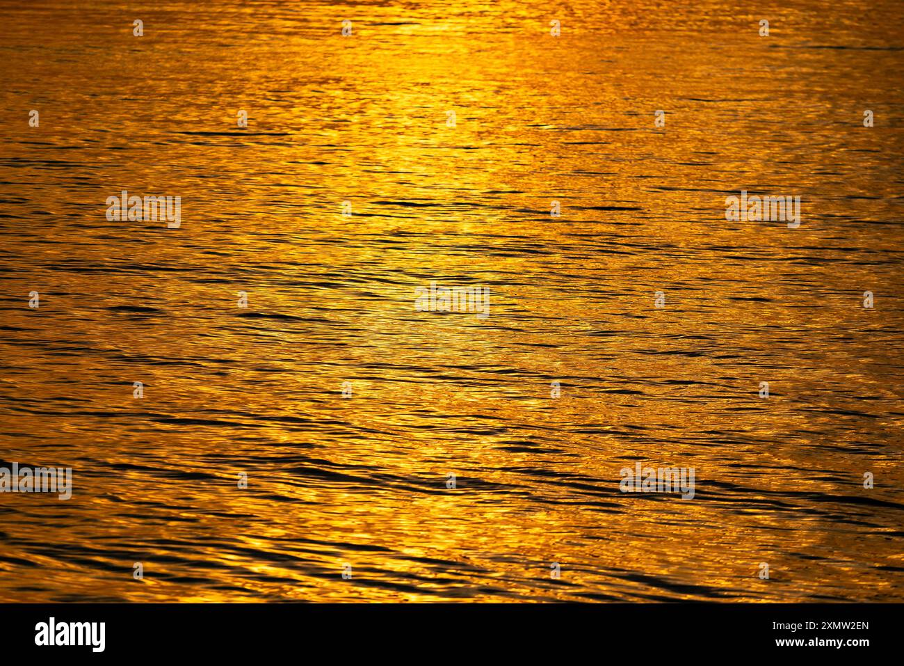 Full frame background of waves sea water rippling and reflecting golden ...