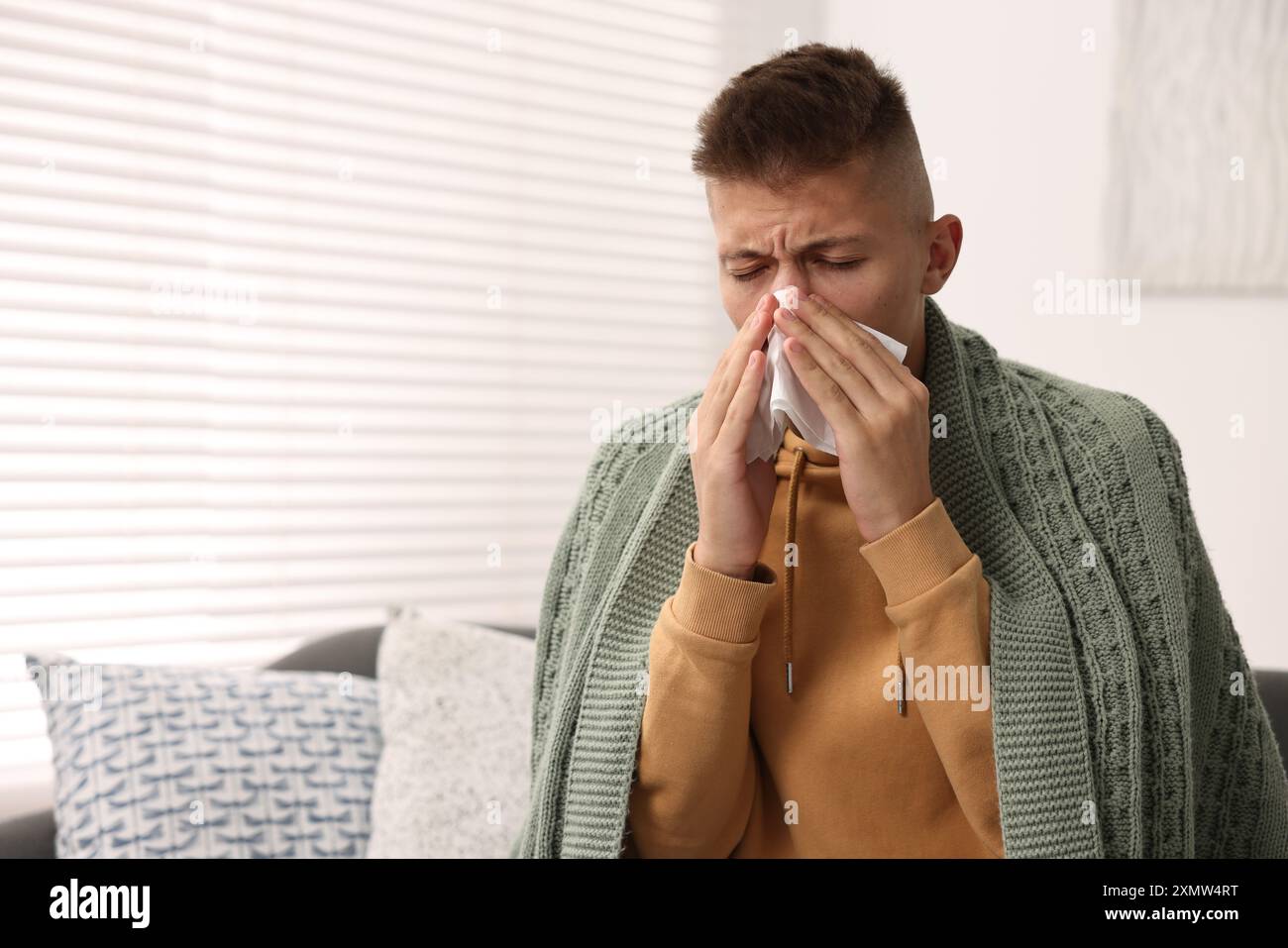 Cold symptom. Young man with runny nose at home Stock Photo - Alamy
