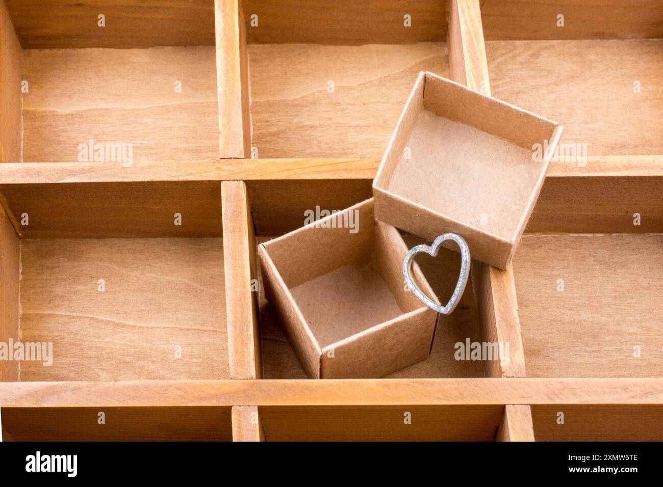 Open cardboard box inside a wooden box with compartments and a heart ...