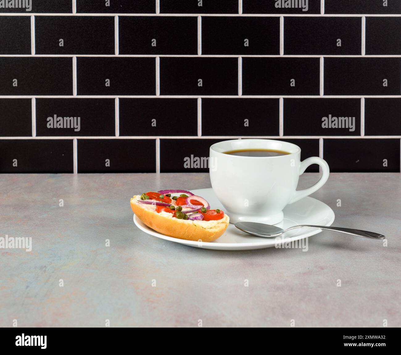 Coffee and bagel on white on pink tinged countertop with black subway ...