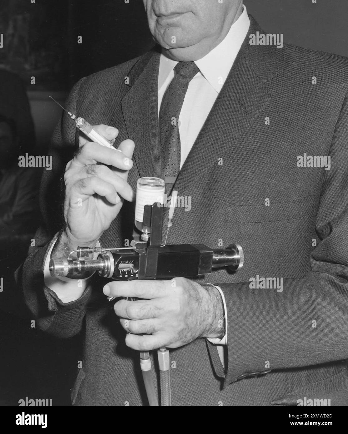 A doctor holds a polio vaccine jet injector and an old fashioned needle ...
