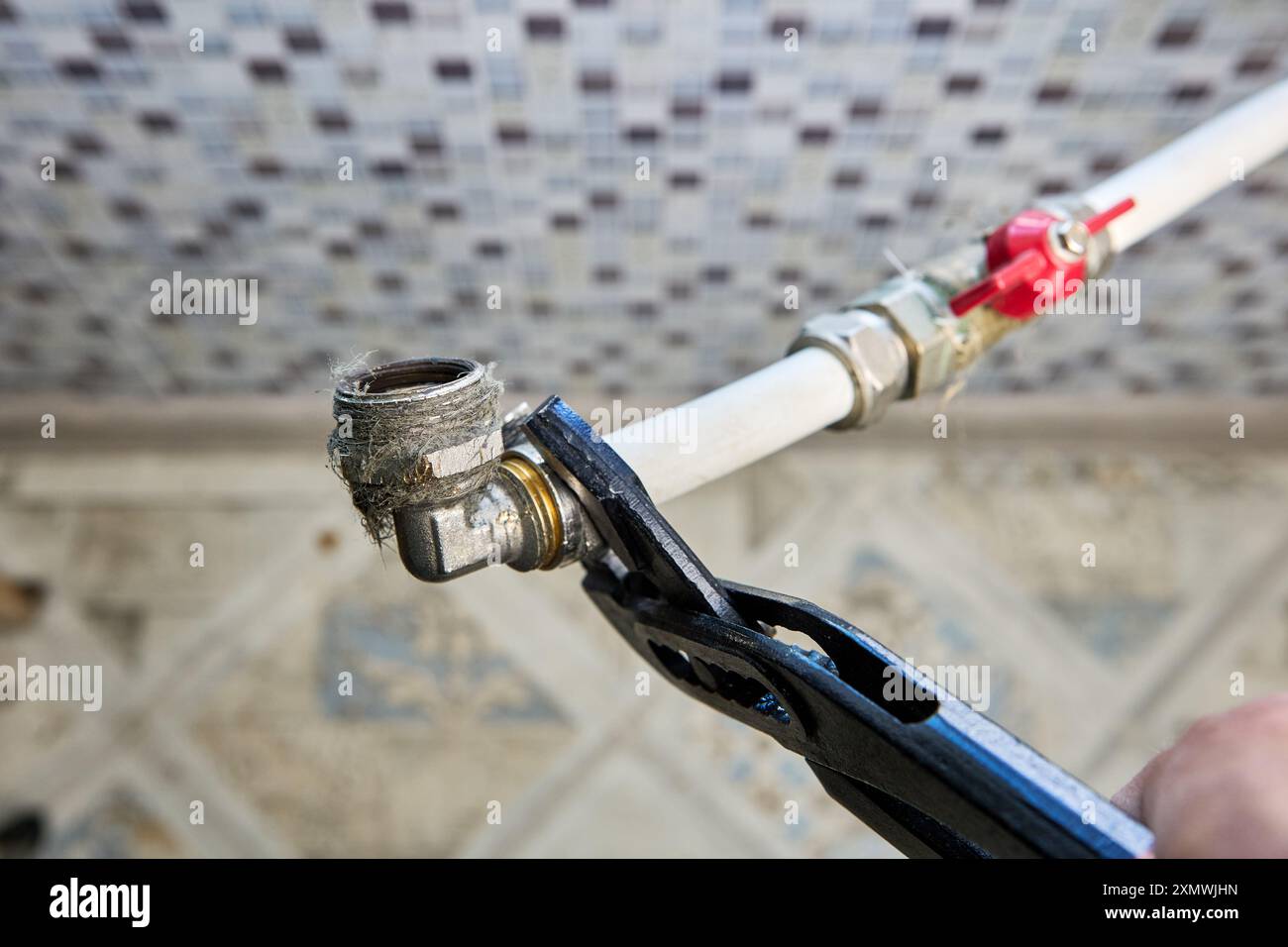 Plumber unscrews elbow adapter compression fitting nut with an ...