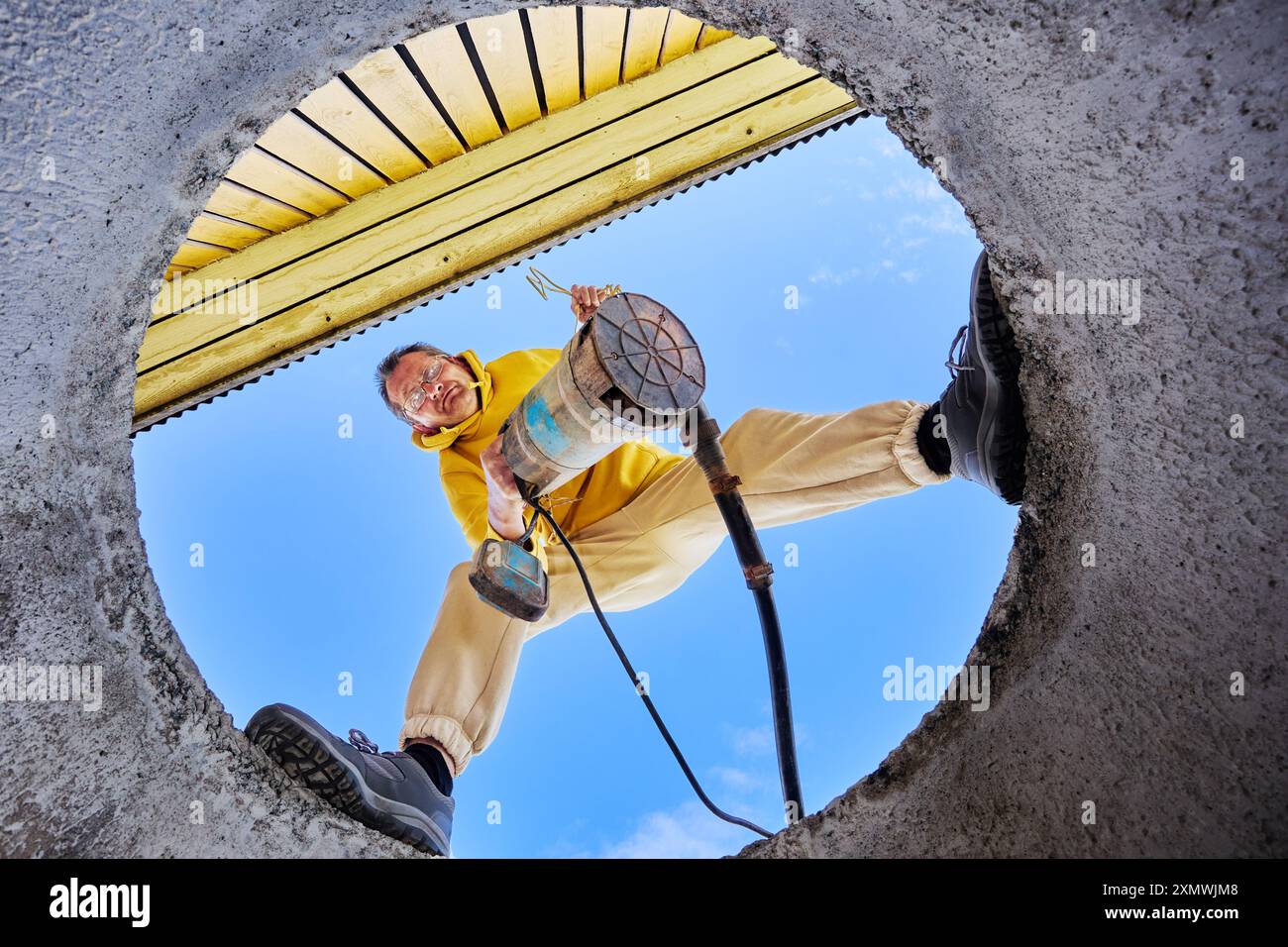 Homeowner installing submersible sewage pump in sump pit to pump out ...