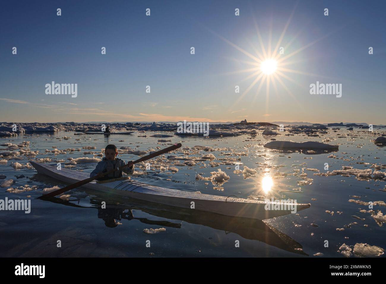 Kayakers, child, kayaking through fjord with icebergs, midnight sun ...