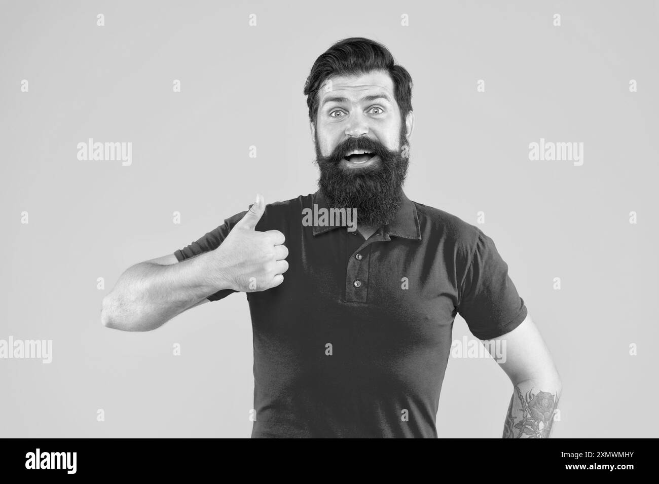 surprised hipster male with beard showing thumb up on yellow background ...