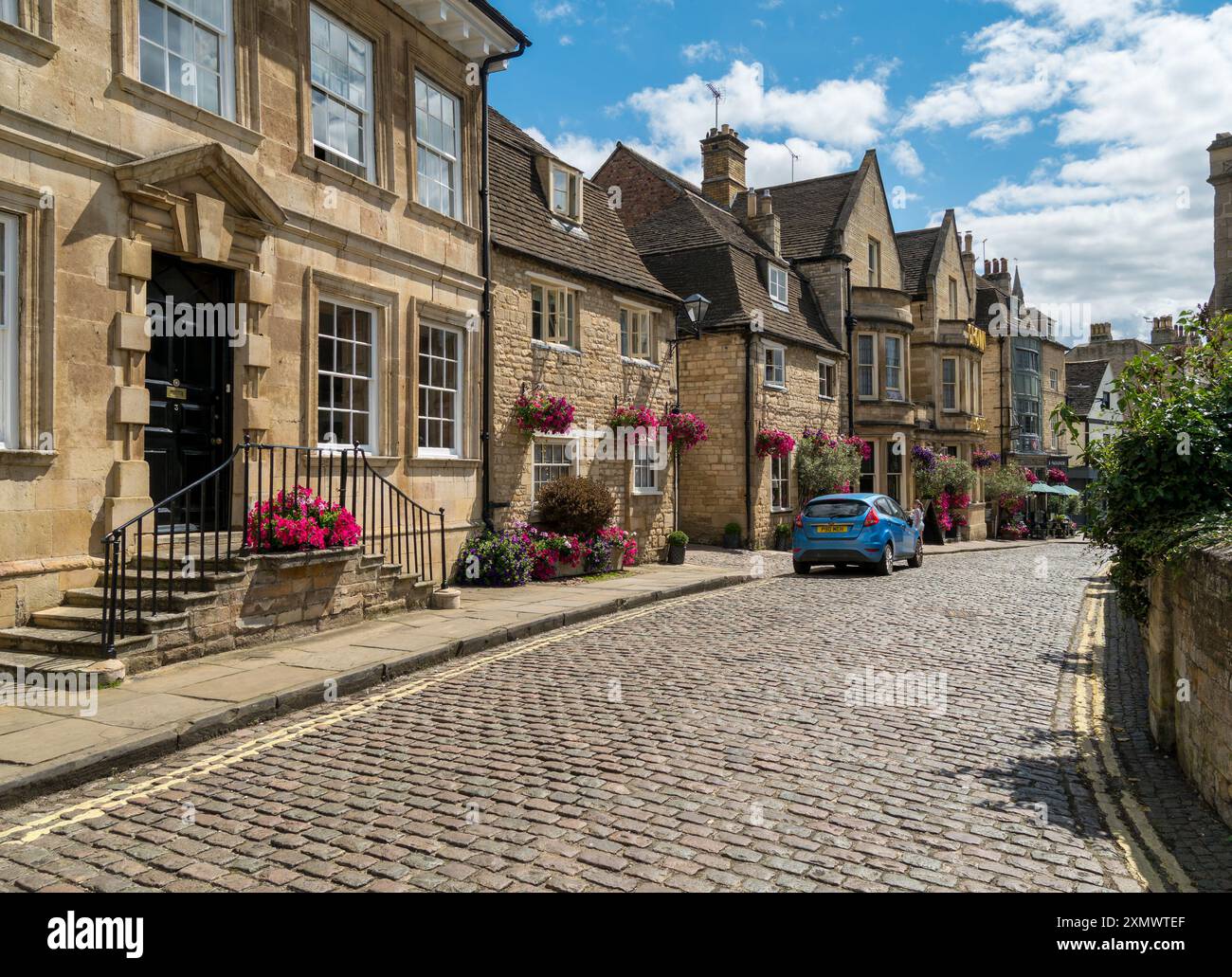 Pretty cobbled street and dressed stone buildings in July, All Saints ...
