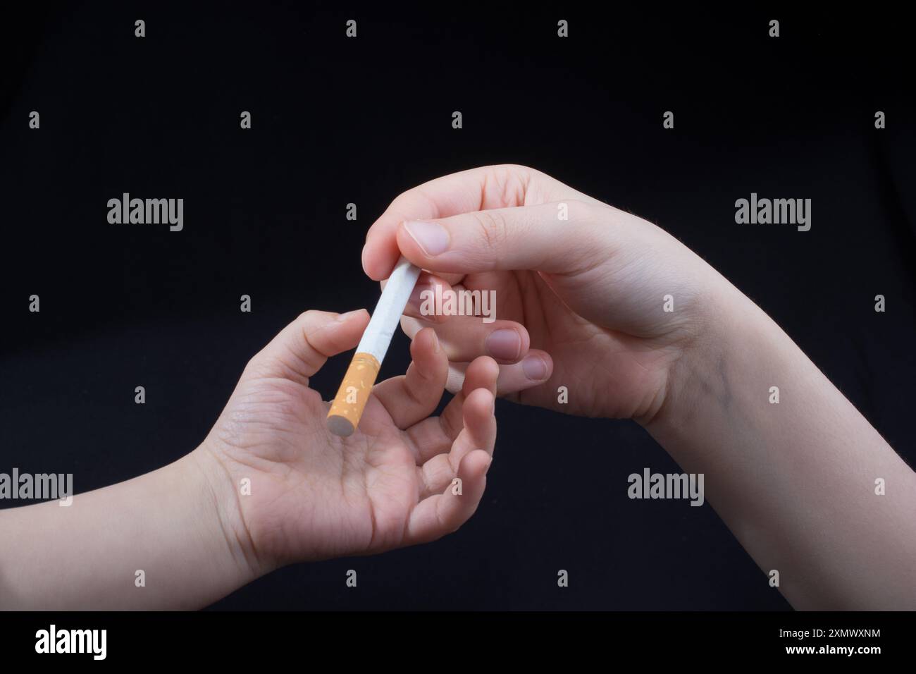 Hand is giving out cigarette on a black background Stock Photo - Alamy
