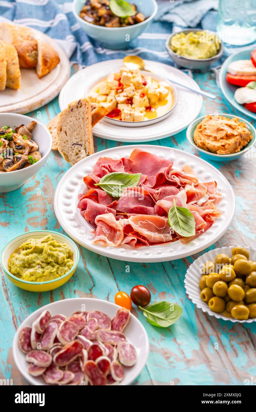 Picnic table with assorted appetizers, raw vegetables, cheese, dips ...