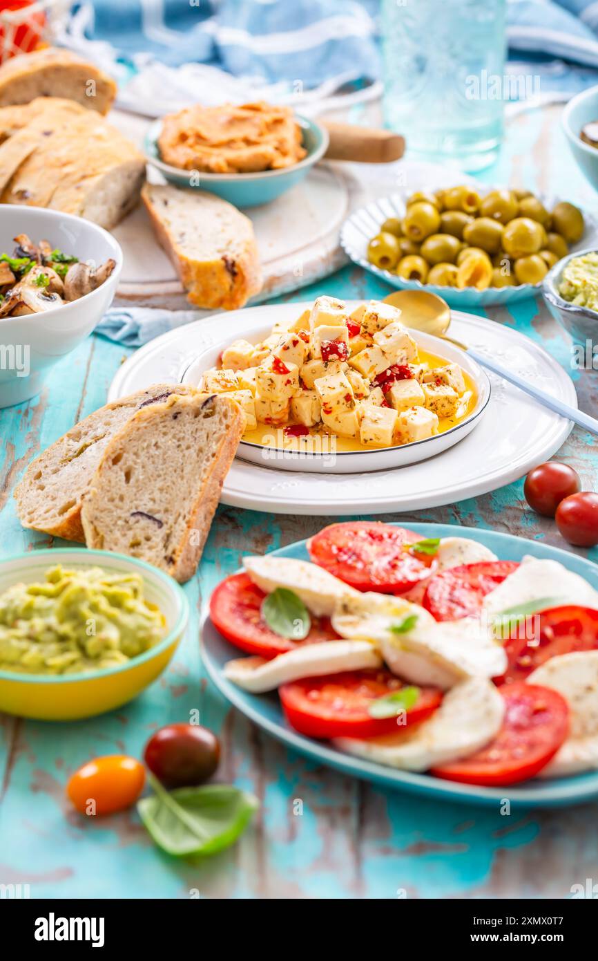 Picnic table with assorted appetizers, raw vegetables, cheese, dips ...