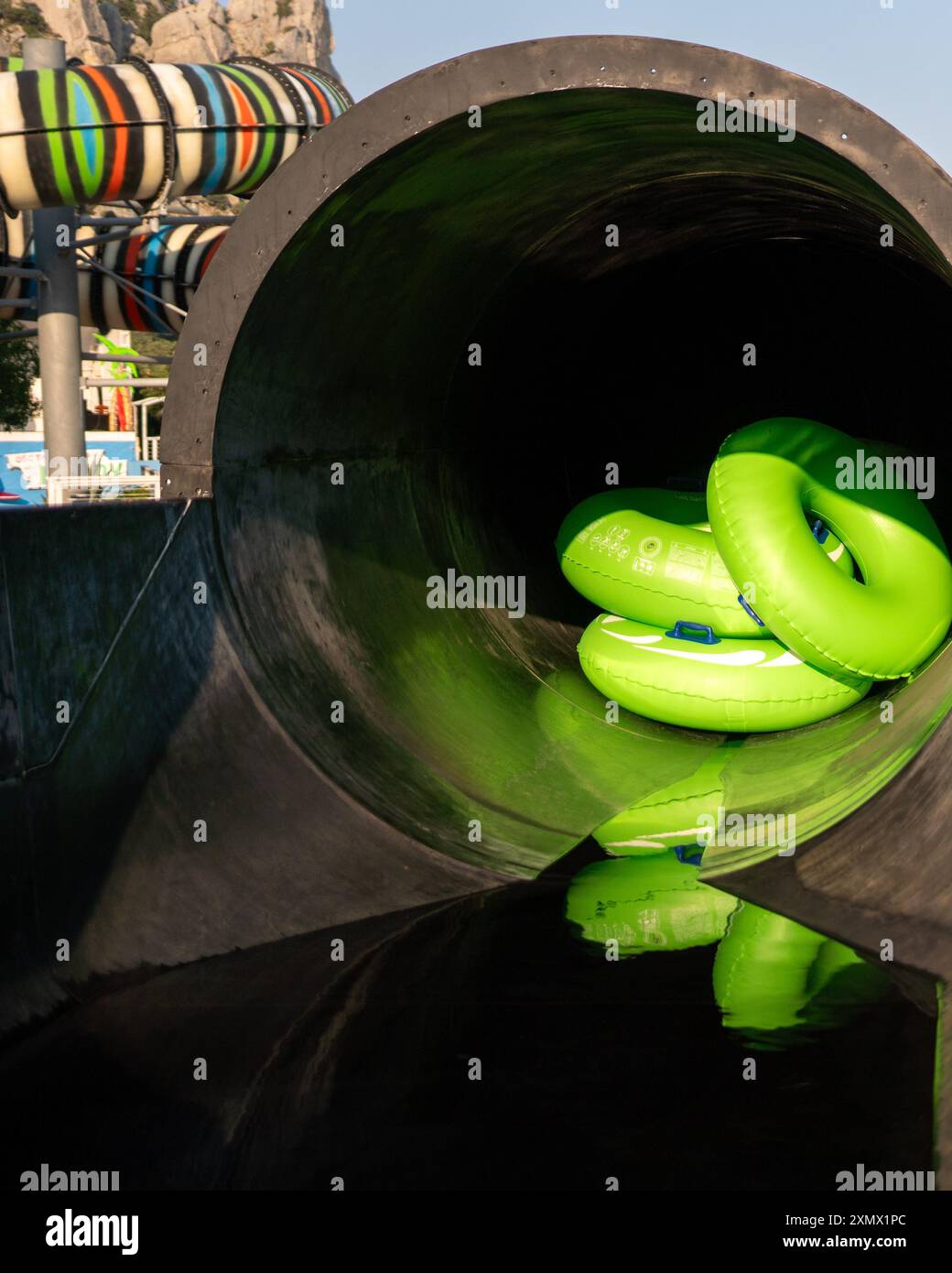 Green inflatable tubes sit in a dark, water-filled tunnel of a water ...