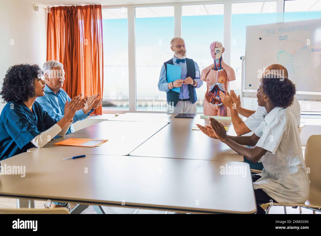 Senior professor teaching anatomy to diverse group of medical students ...