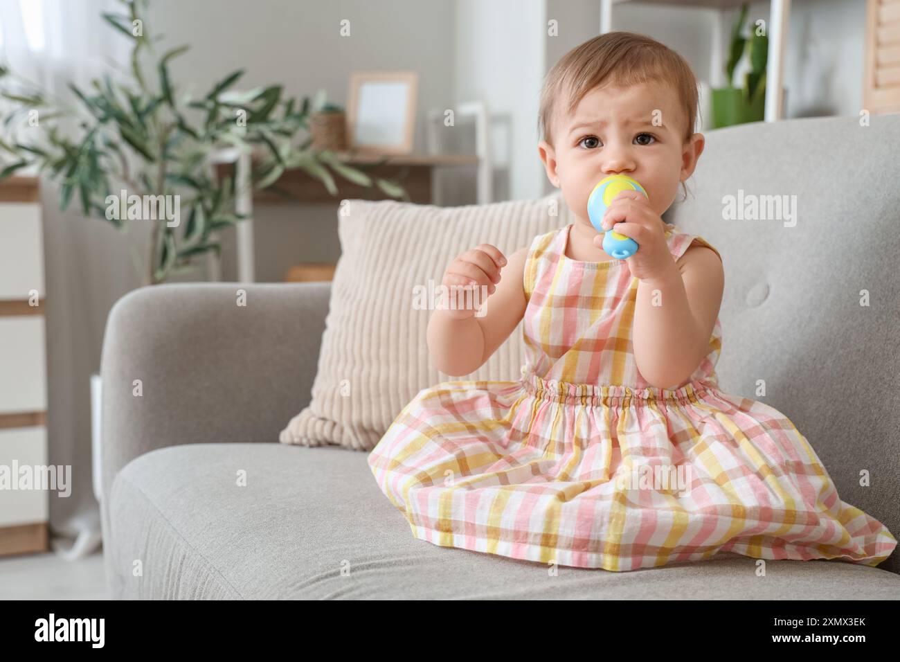 Cute little baby with nibbler eating food on sofa at home Stock Photo ...