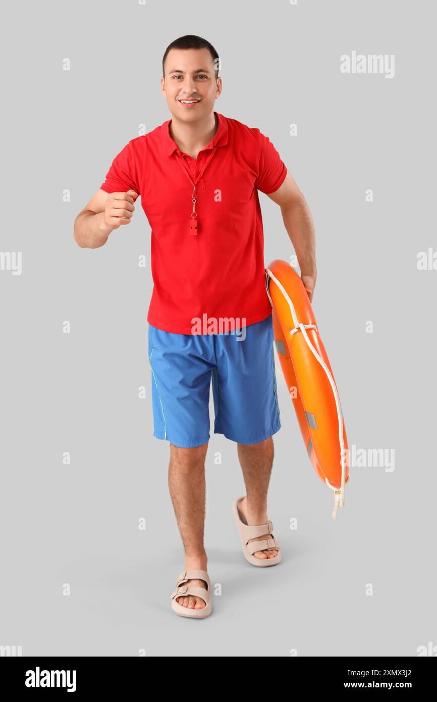Happy male lifeguard with ring buoy running on grey background Stock ...